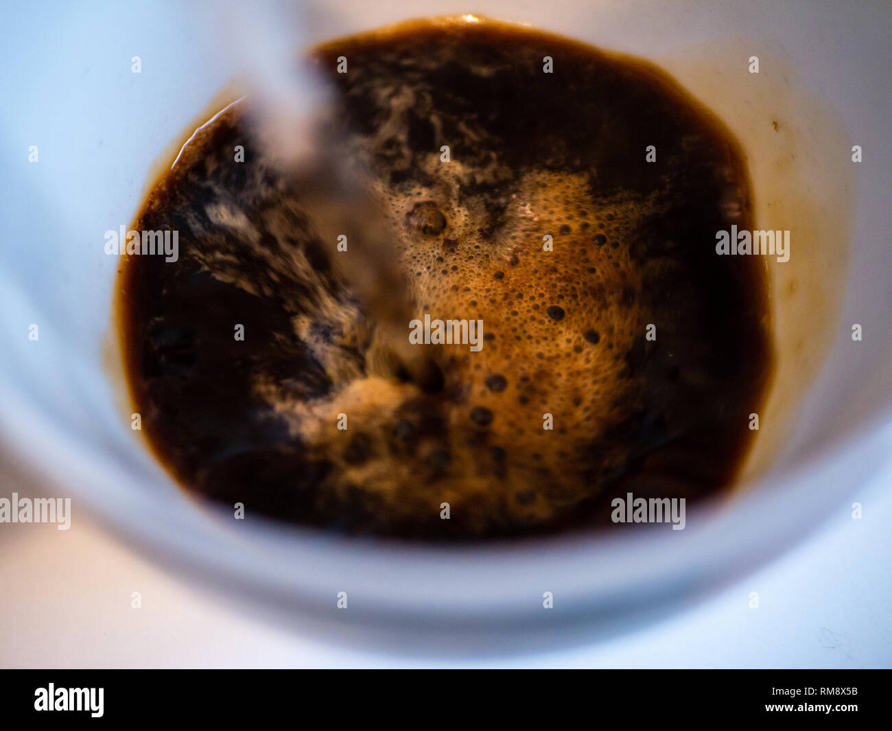 Top view of boiling water being poured into a cup with instant coffee ...
