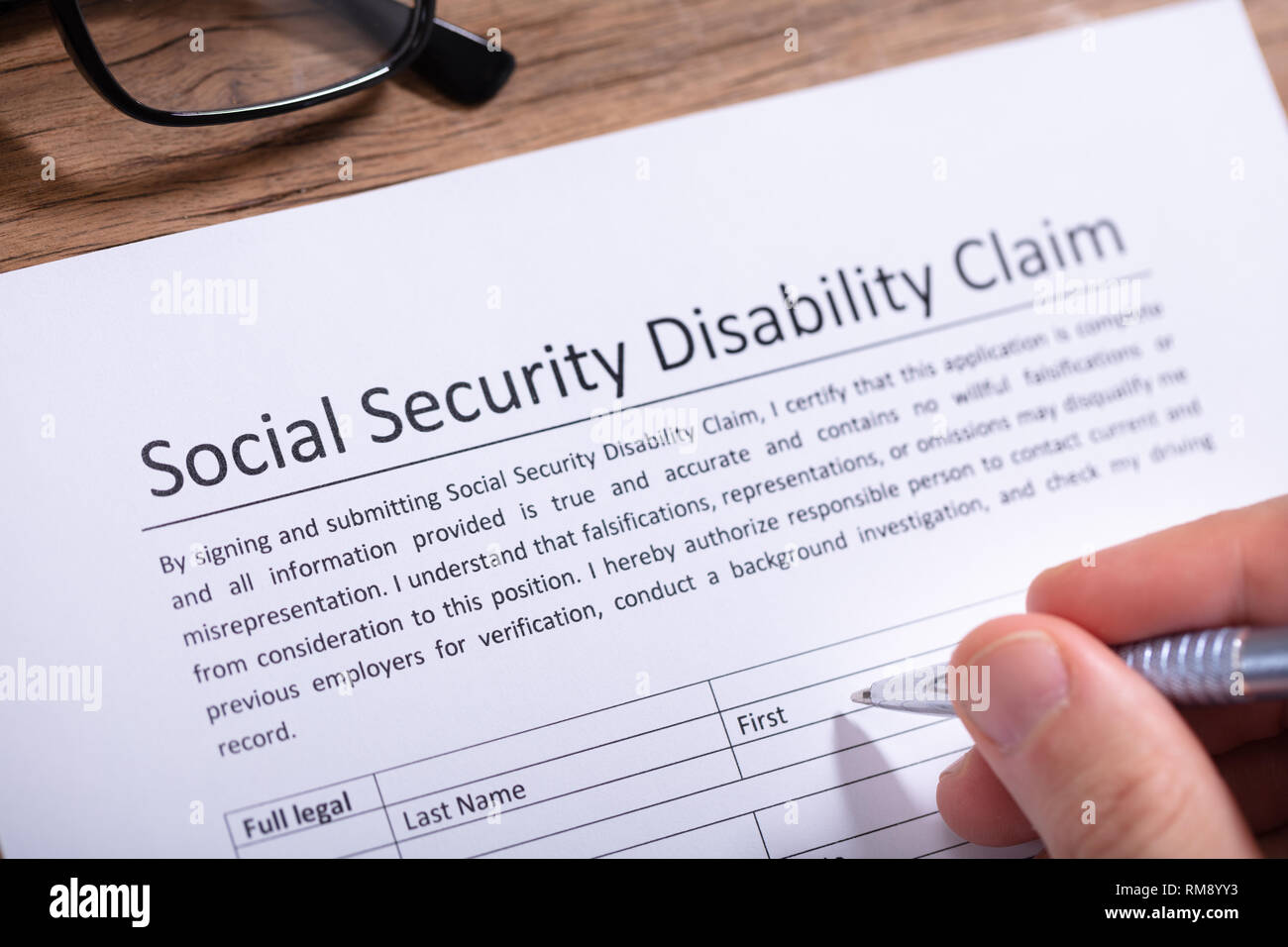 Close-up Of A Person's Hand Filling Social Security Disability Claim ...