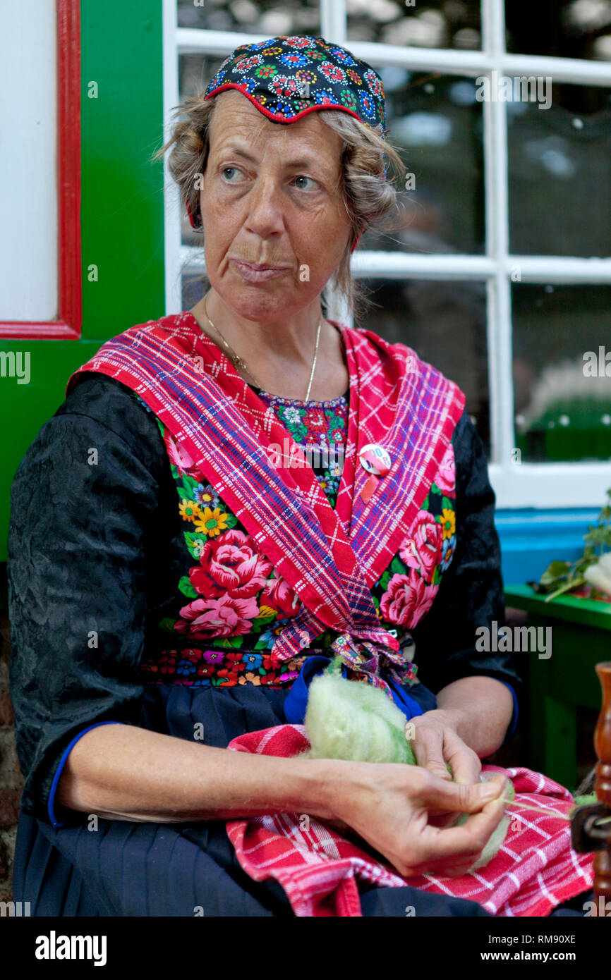 Woman in traditional Dutch outfit spinning wool in front of an ...