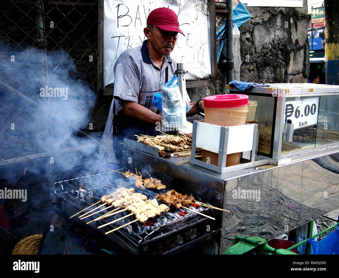 ANTIPOLO CITY, PHILIPPINES - JANUARY 26, 2019: Street vendors grill and ...