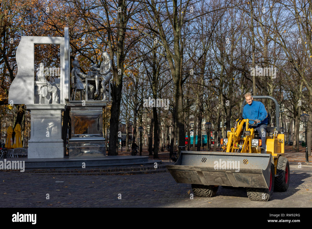 Worker on a dirt digging truck passing a statue in the streets of The ...
