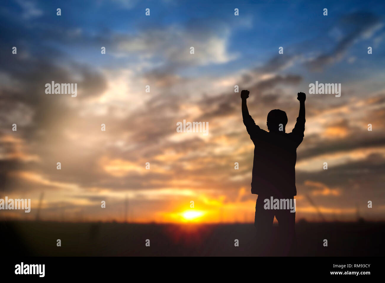 Silhouette of man with raised hands over blur cross concept for ...
