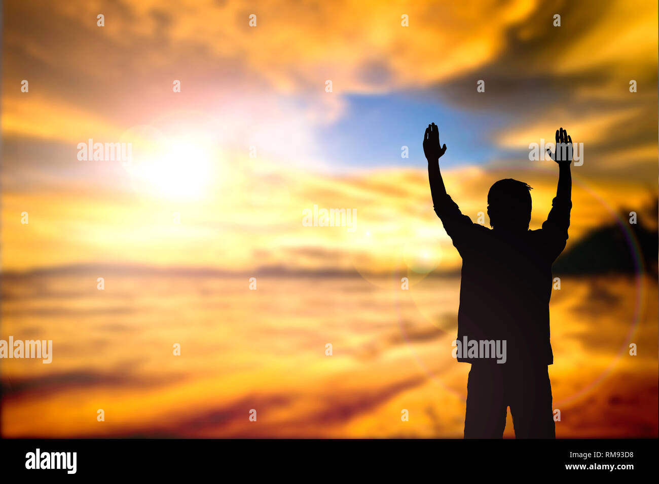 Silhouette of man with raised hands over blur cross concept for ...