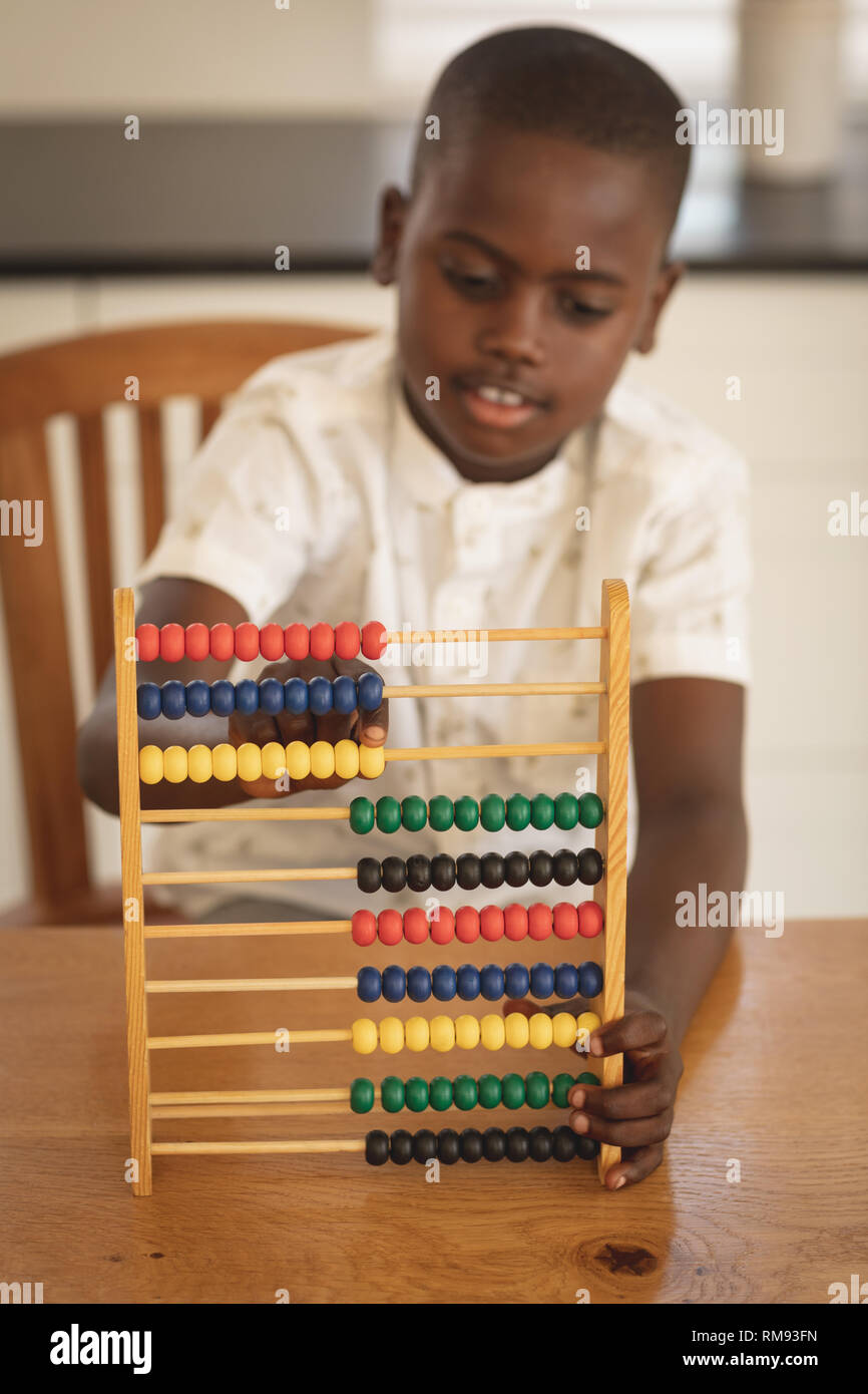 African American boy learning mathematics with abacus on dining table ...