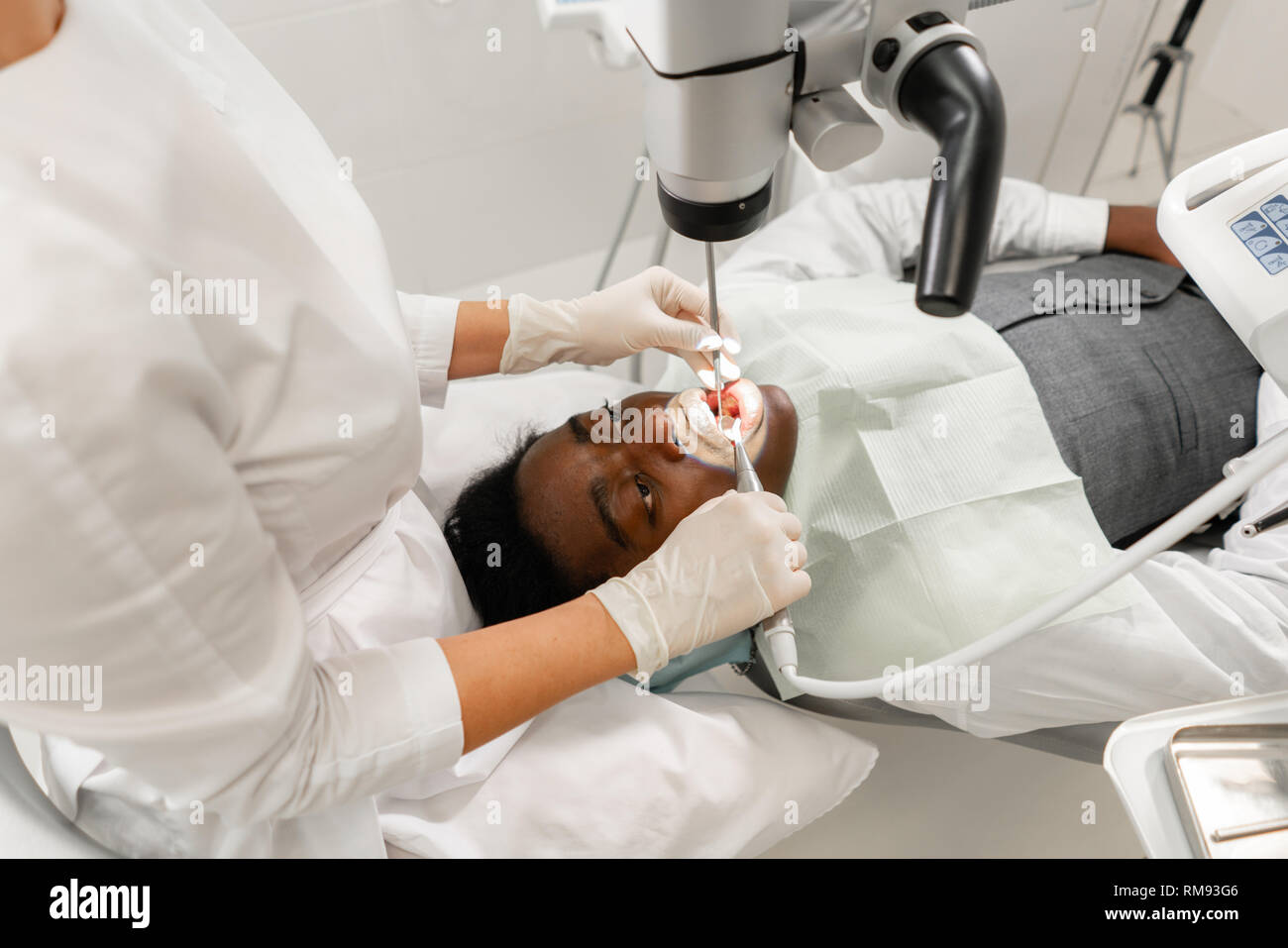 Young woman dentist treating root canals using microscope in the dental ...