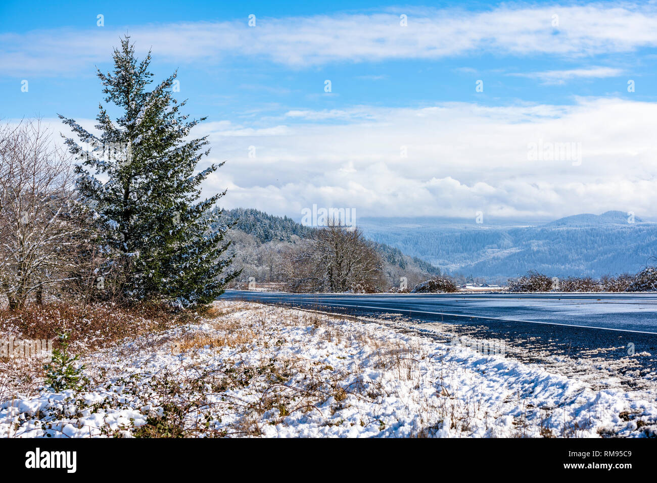 Winter landscape with wet melting road and hills with snow-covered ...