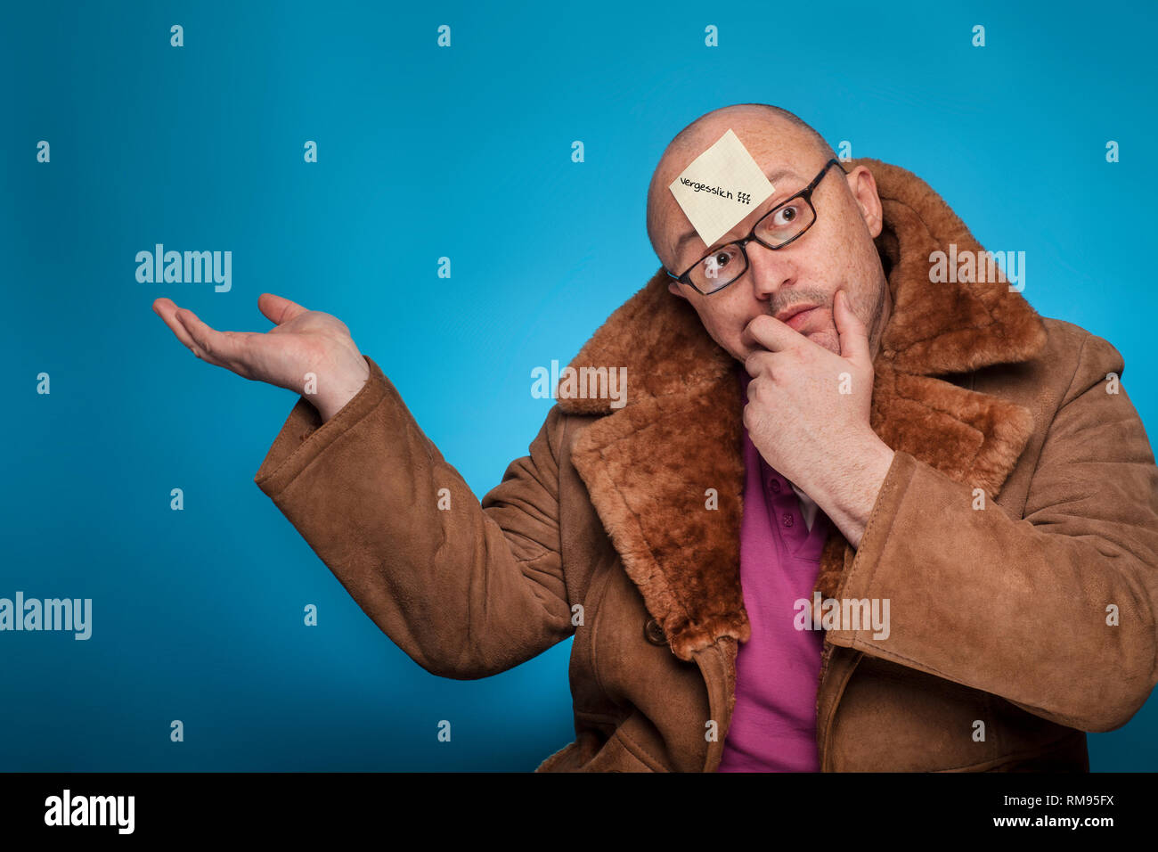 An elderly bald man in a fur coat has a blank post it on the forehead ...