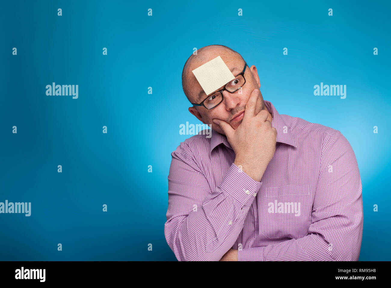 A businessman in a piked shirt has a blank post it on the forehead, on ...