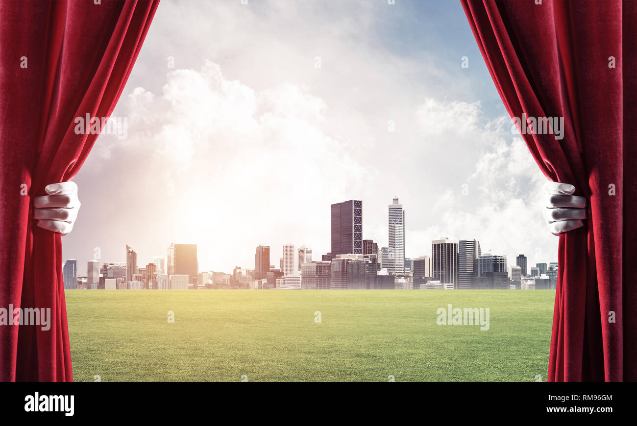 Green meadow behind red curtain and hand holding it Stock Photo - Alamy