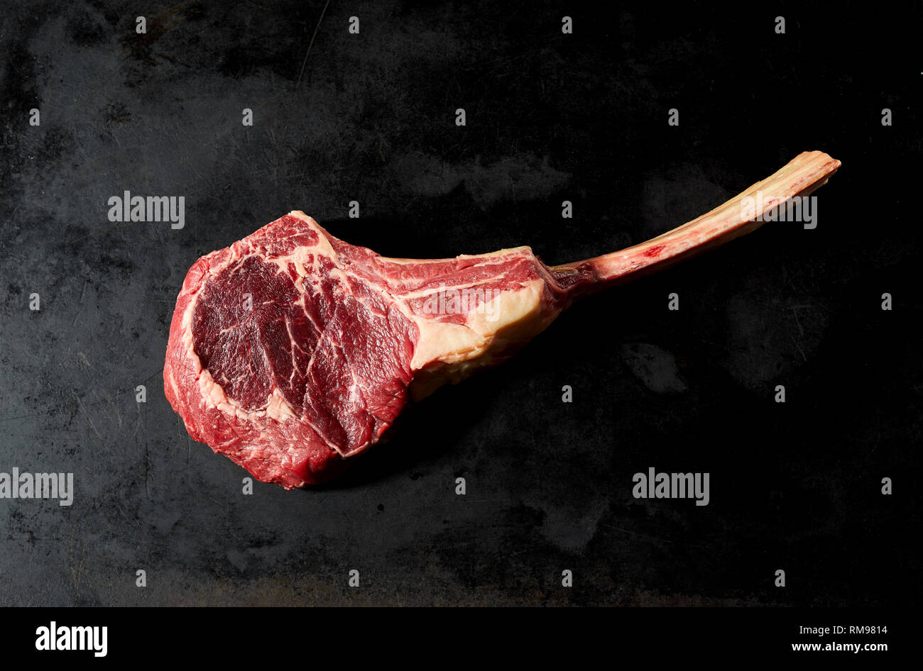 Single bone-in raw ribeye or Delmonico beef steak on blackened metal ...