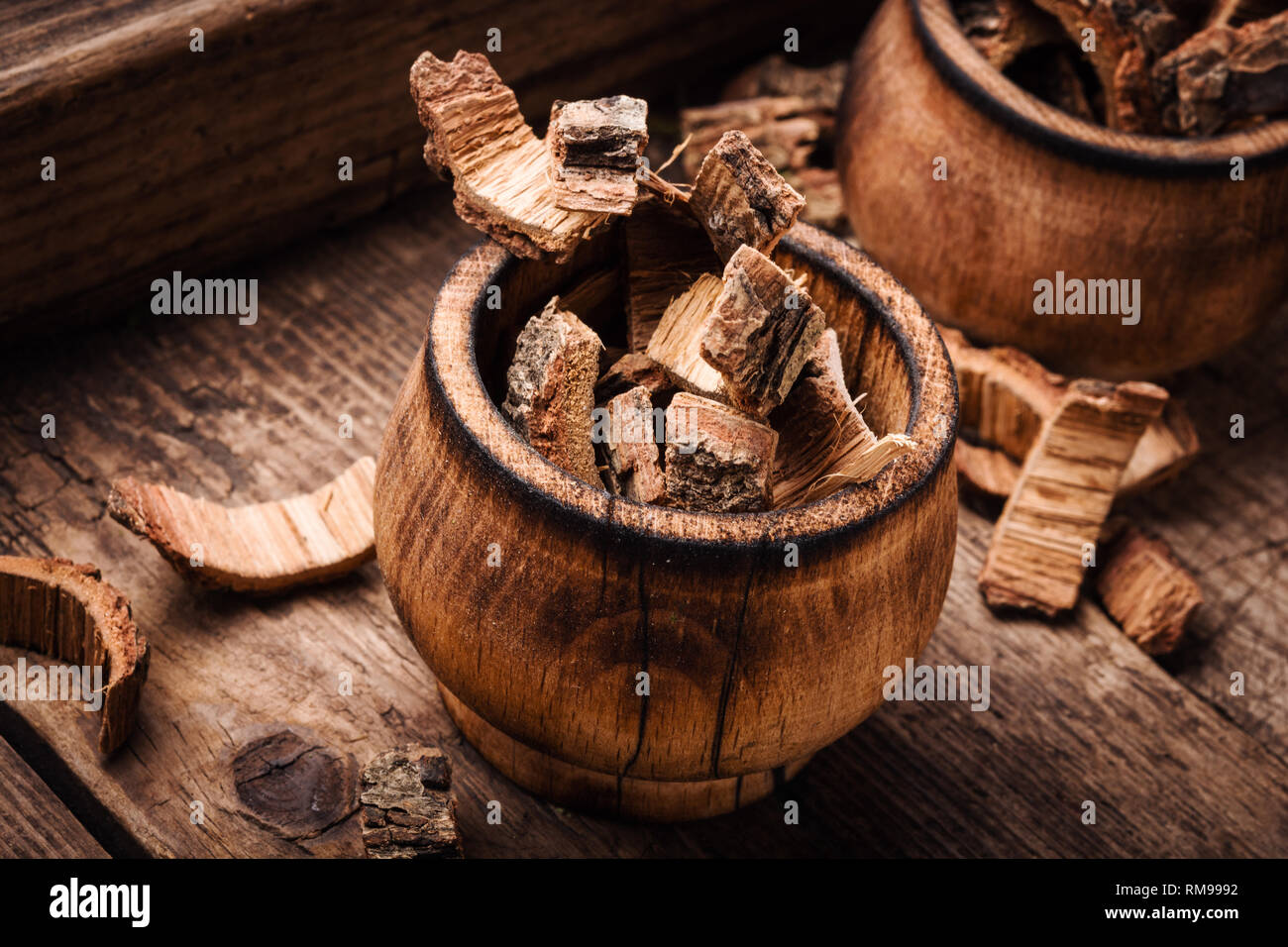 Oak bark in mortar on a dark wooden table. Oak in herbal medicine ...
