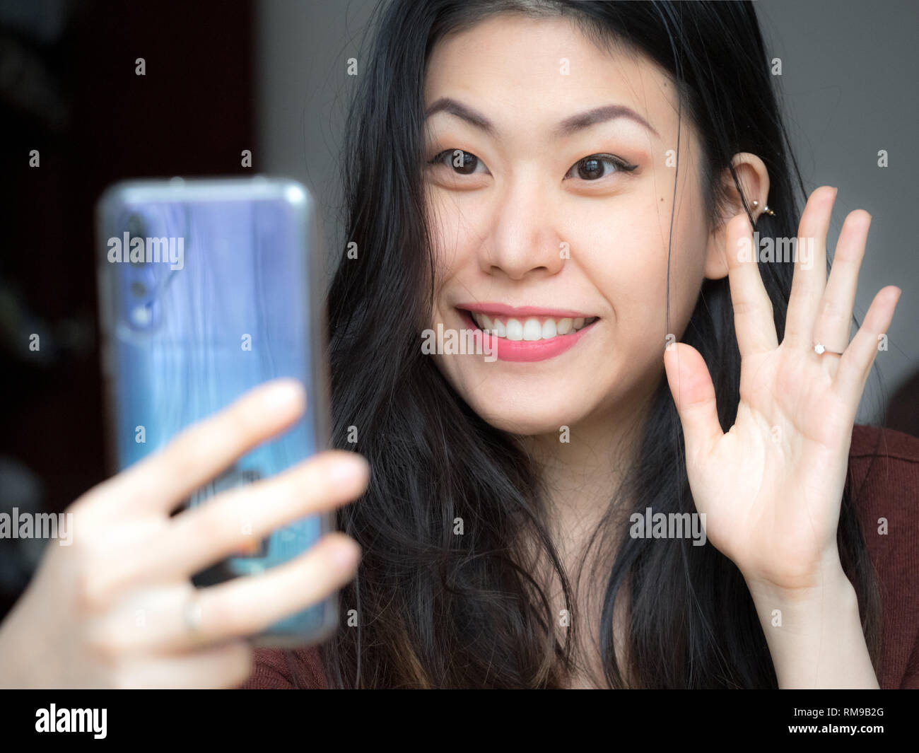 Asian young beautiful cheerful woman smiling, waving and saying hi to ...