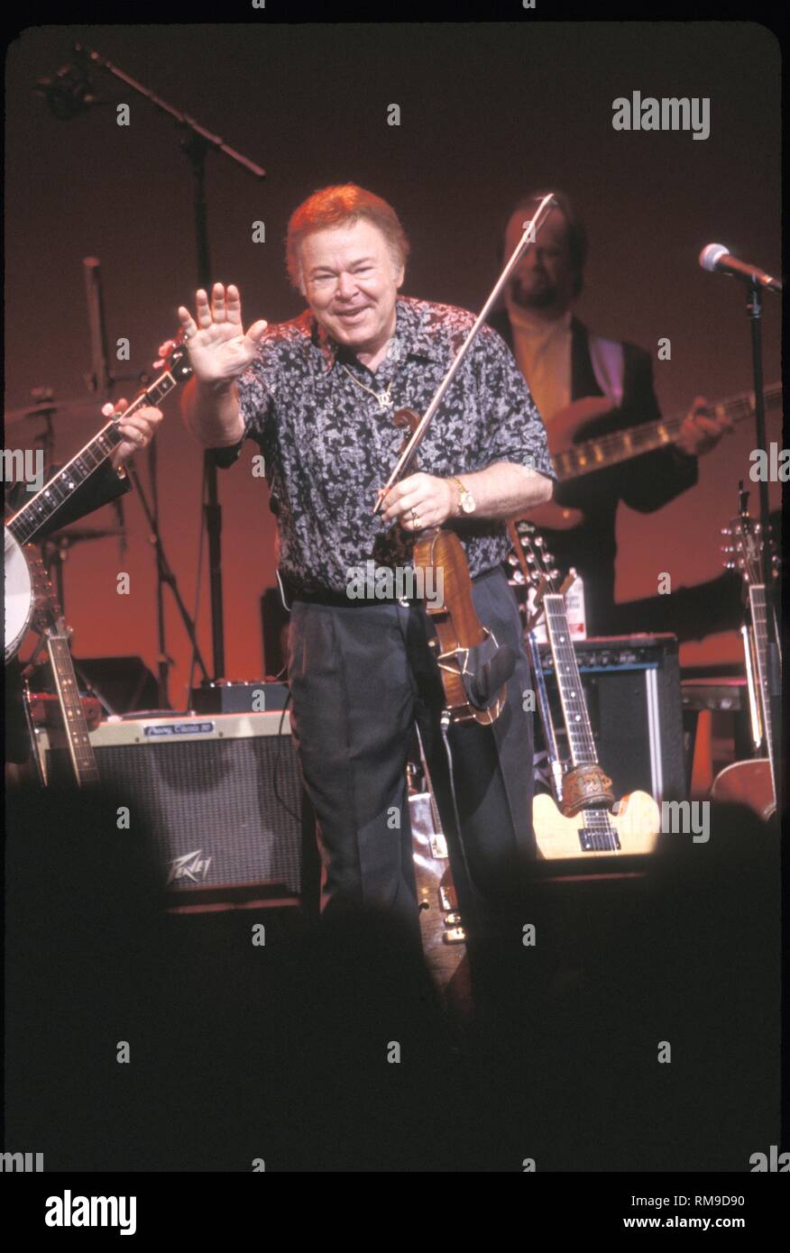 Musician Roy Clark is shown performing on stage during a "live" concert ...