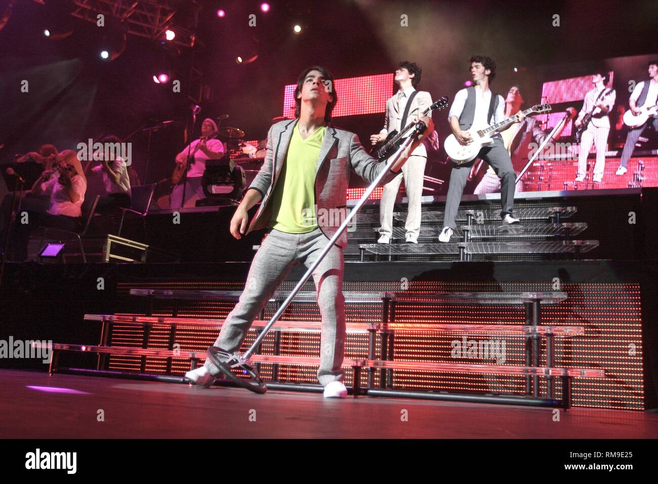 The Jonas Brothers are shown performing on stage during a "live ...