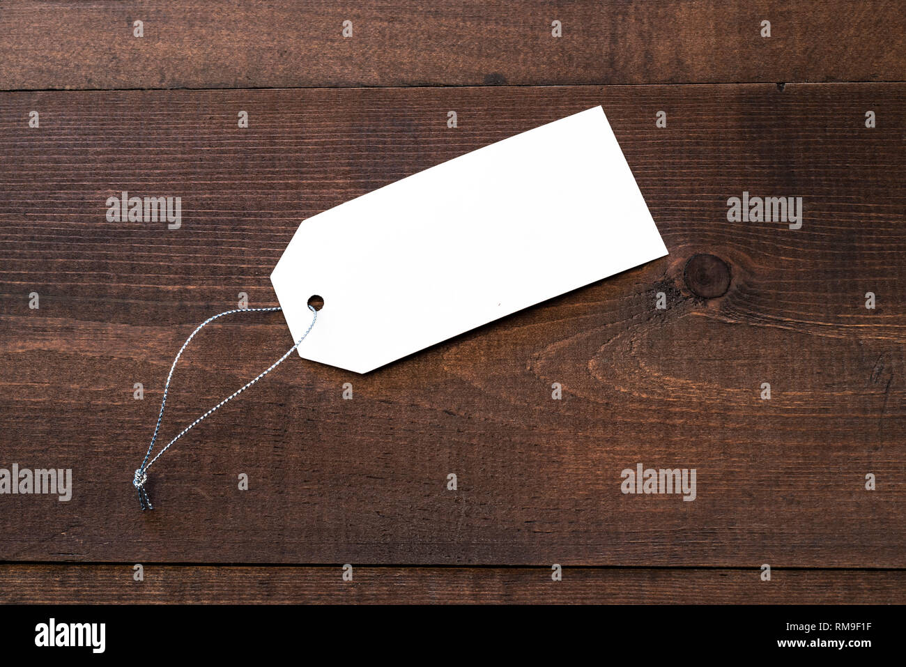 Plain, white gift tag or label with metallic cord Stock Photo - Alamy