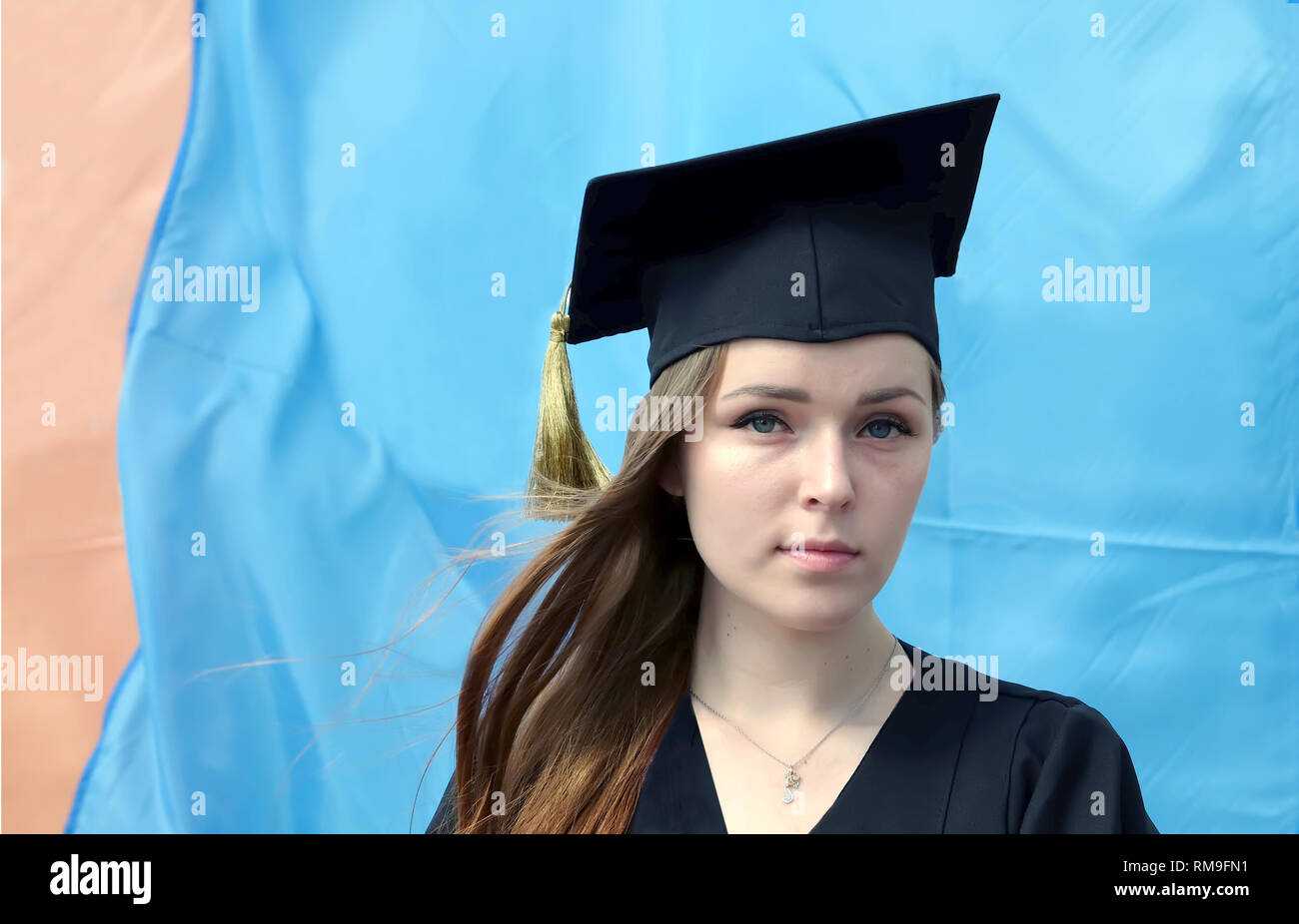 Graduate attractive young girl with red hair dressed in black mantle ...
