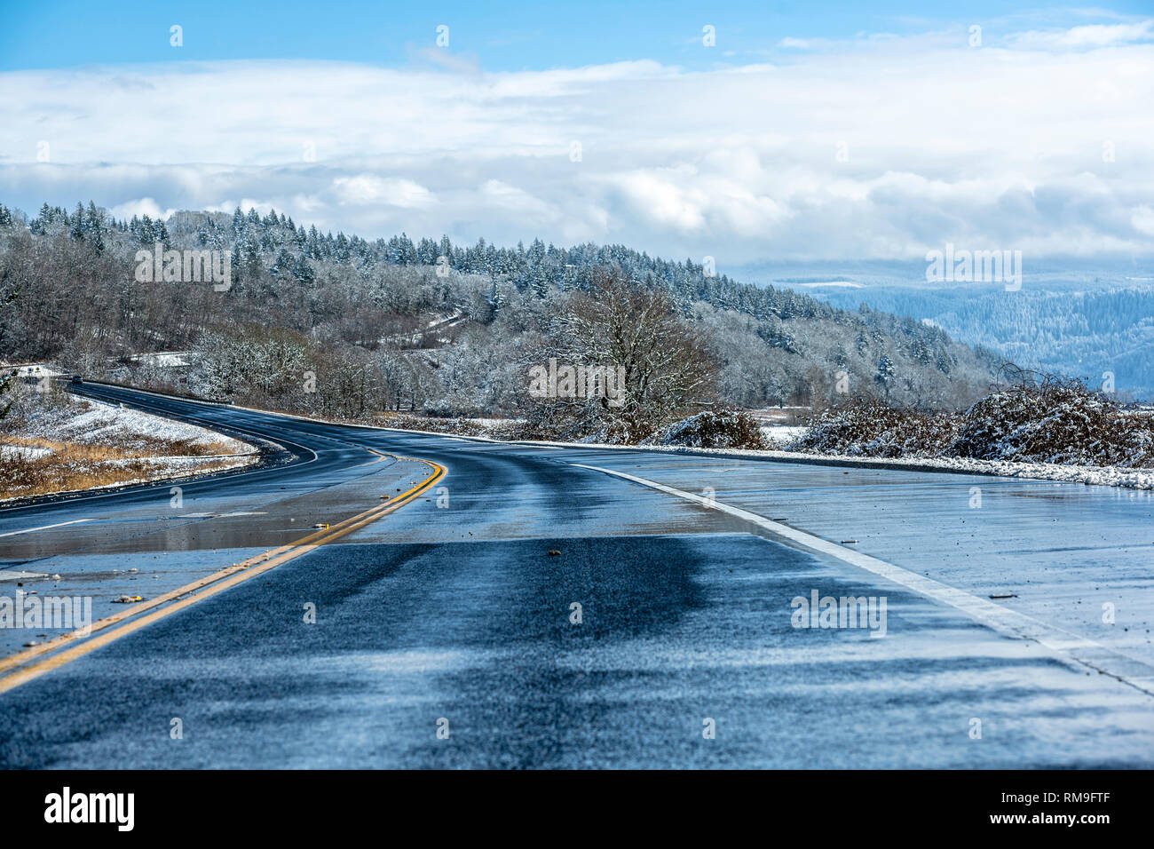 Winter landscape with wet melting road and hills with snow-covered ...
