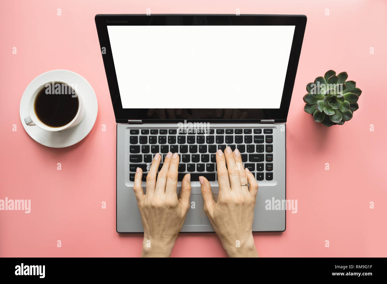Woman typing by laptop on office pink table. Top view with space for ...