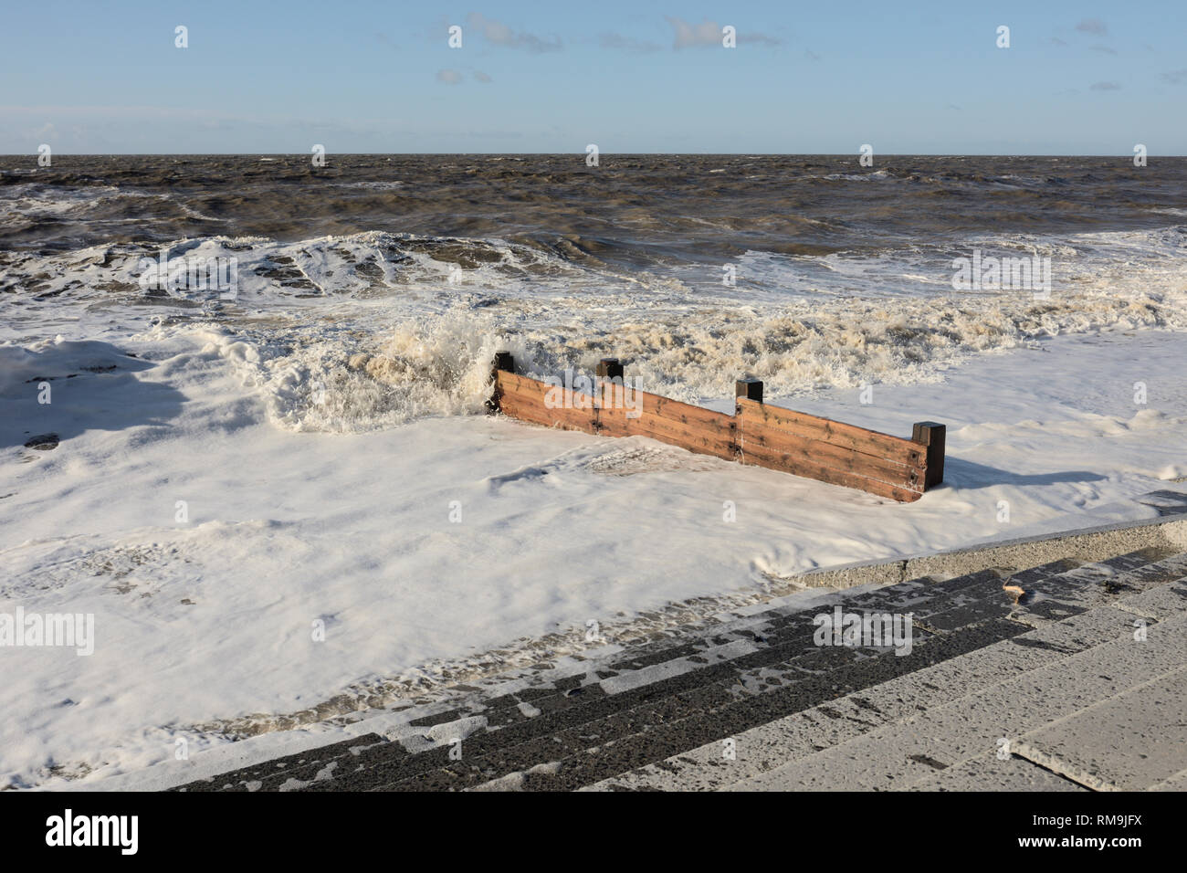 Waves breaking against wooden groyne and concrete stepped revetment in ...
