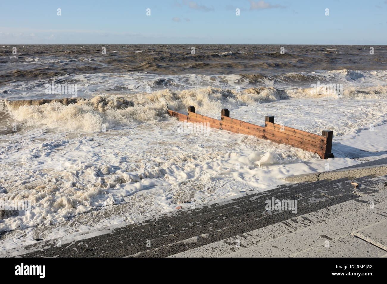 Waves breaking against wooden groyne and concrete stepped revetment in ...
