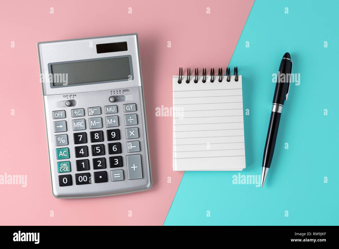 Calculator on pastel pink and blue background with notepad and pen ...
