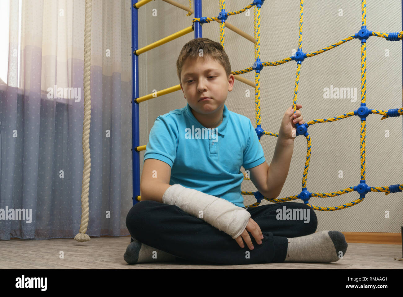 Sad child with a broken arm in the home environment . The cast on the ...
