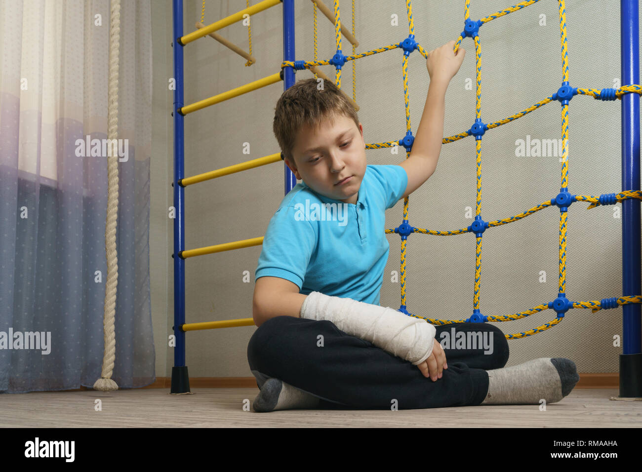 Sad child with a broken arm in the home environment . The cast on the ...