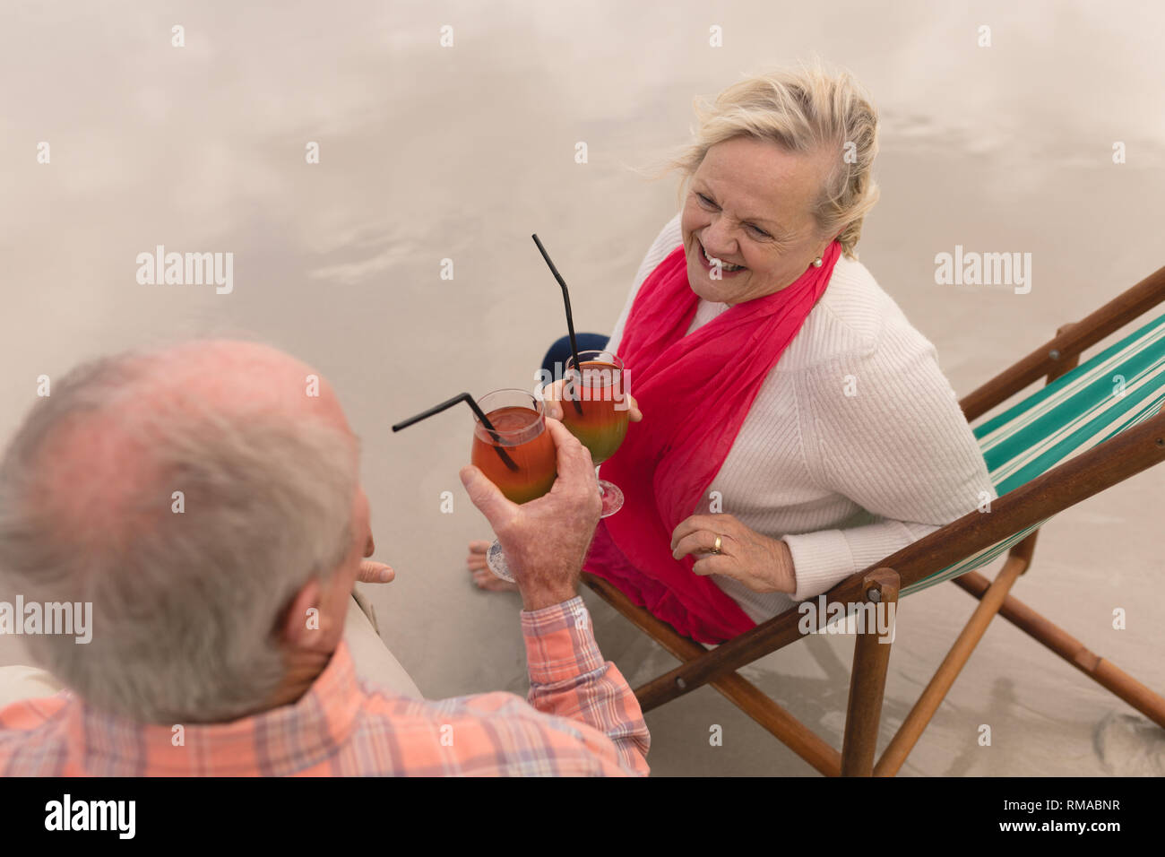 Senior couple toasting glasses of cocktail drinks in a sun lounger ...