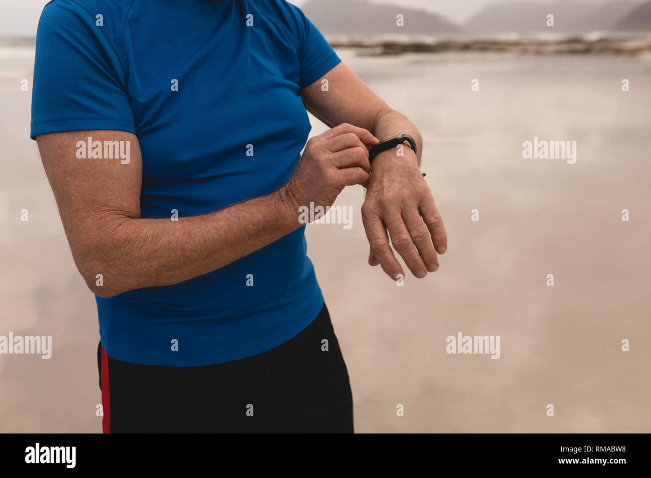 Senior man using smartwatch at the beach Stock Photo - Alamy