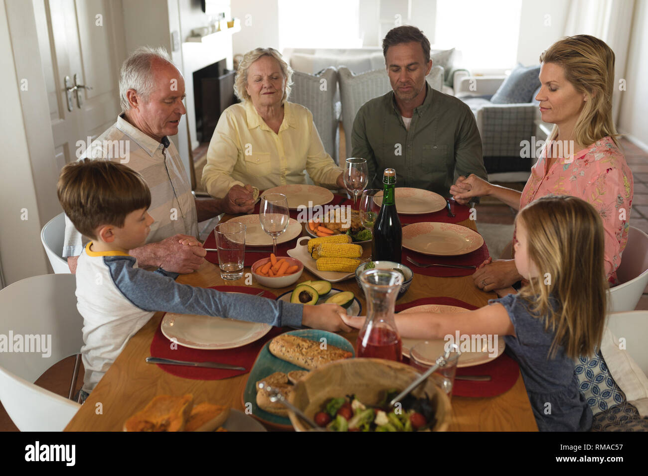 Family praying together before having meal on dining table Stock Photo ...