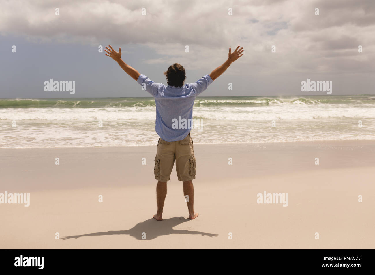 Man standing with arms outstretched on the beach Stock Photo - Alamy