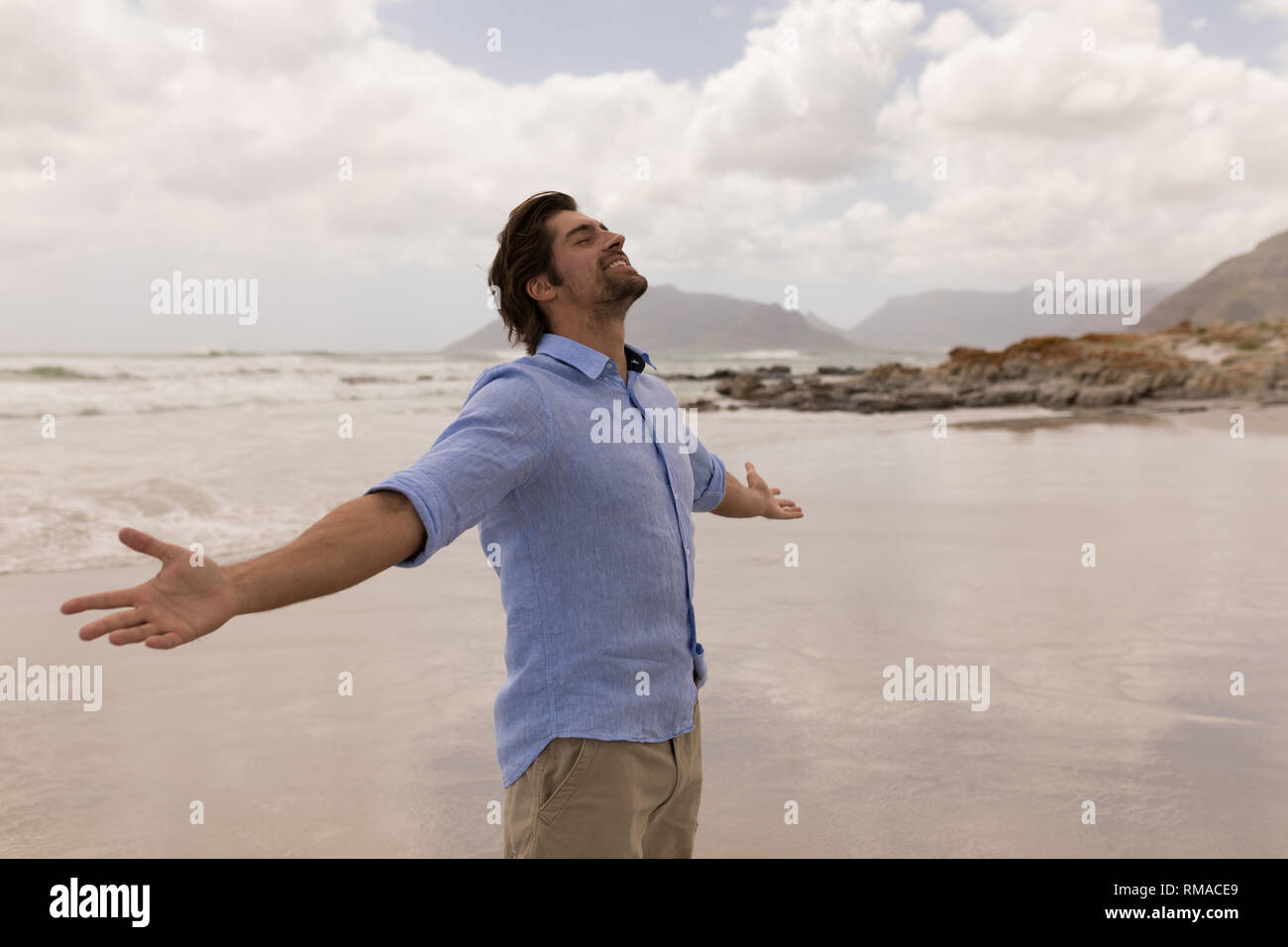 Man standing with arms outstretched on the beach Stock Photo - Alamy