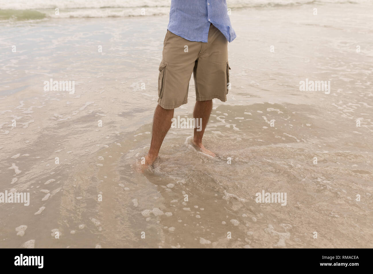 Man standing on sea water on the beach Stock Photo - Alamy
