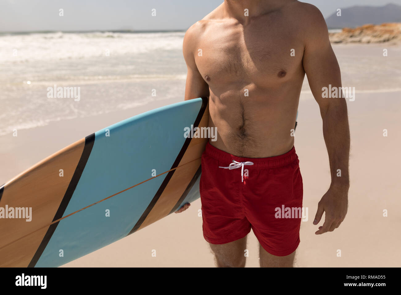 Shirtless young male surfer with surfboard standing on beach Stock ...