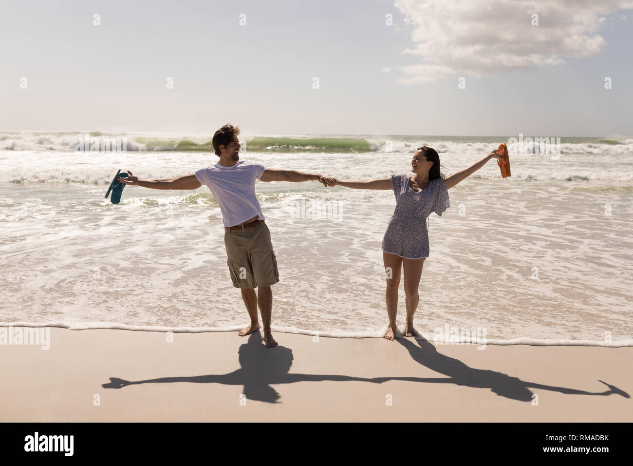 Romantic happy young couple with arms outstretched and holding hands ...