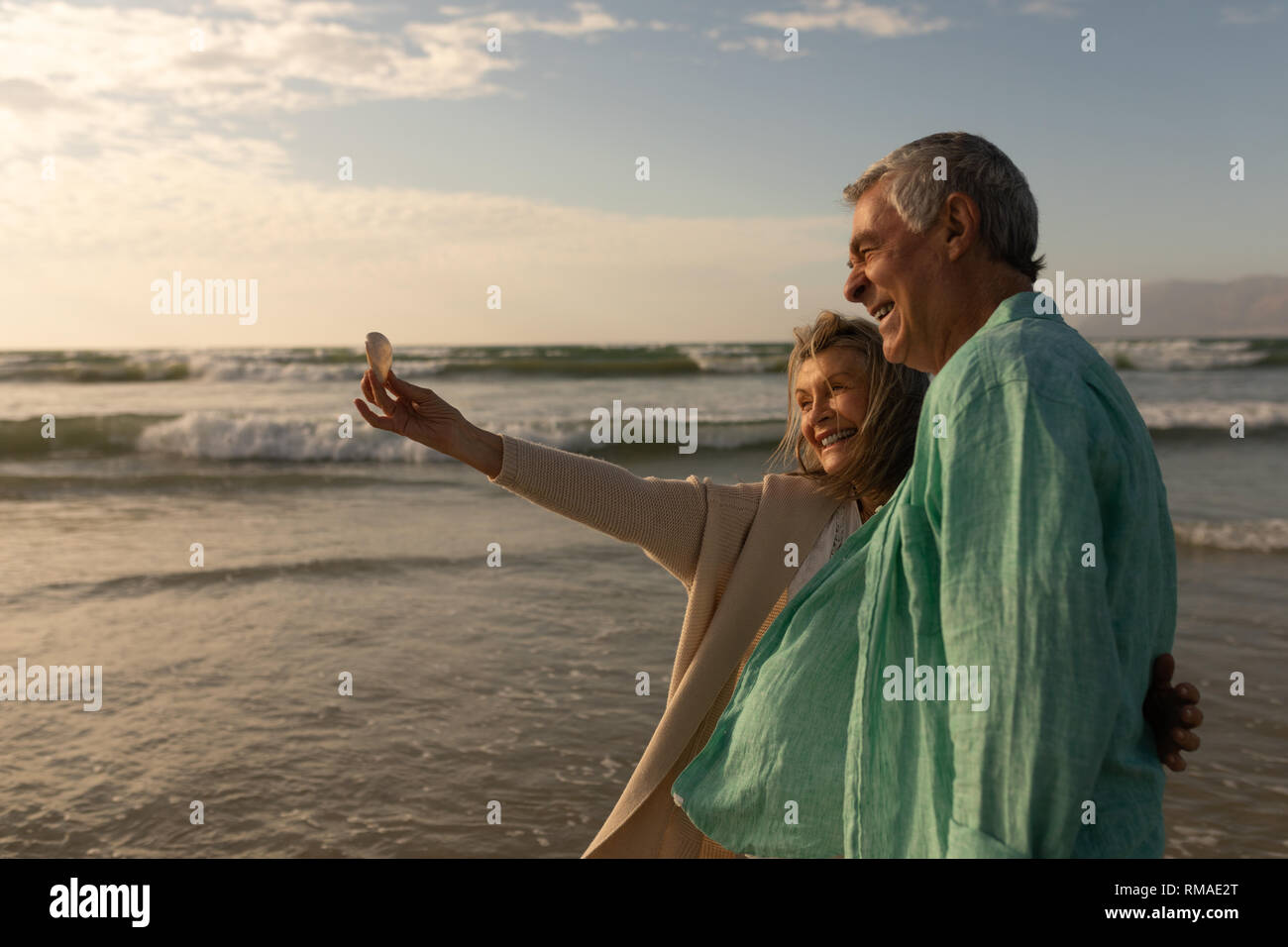 Senior couple holding sea shell on the beach Stock Photo - Alamy