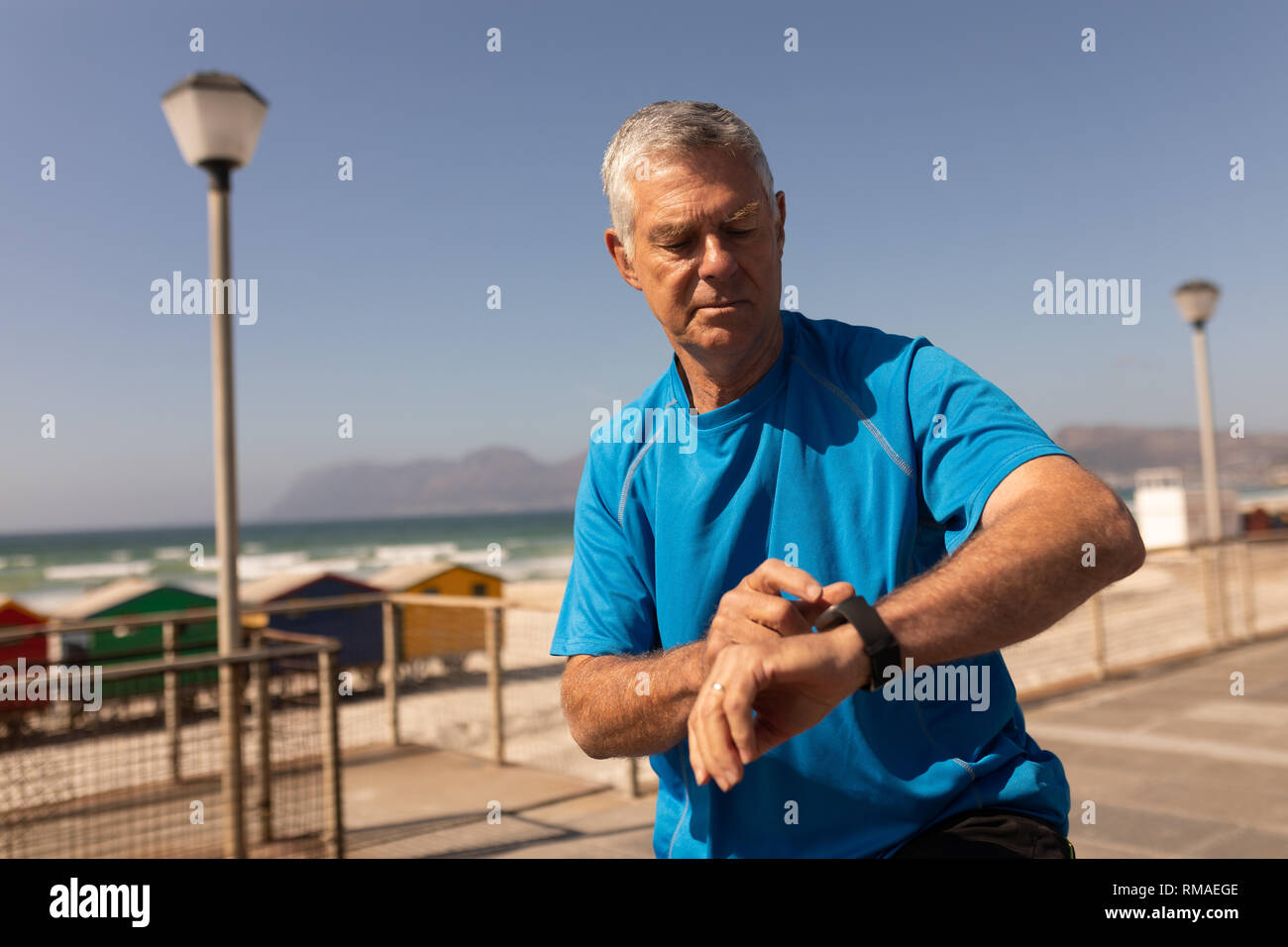 Senior man checking time on smartwatch at beach Stock Photo - Alamy