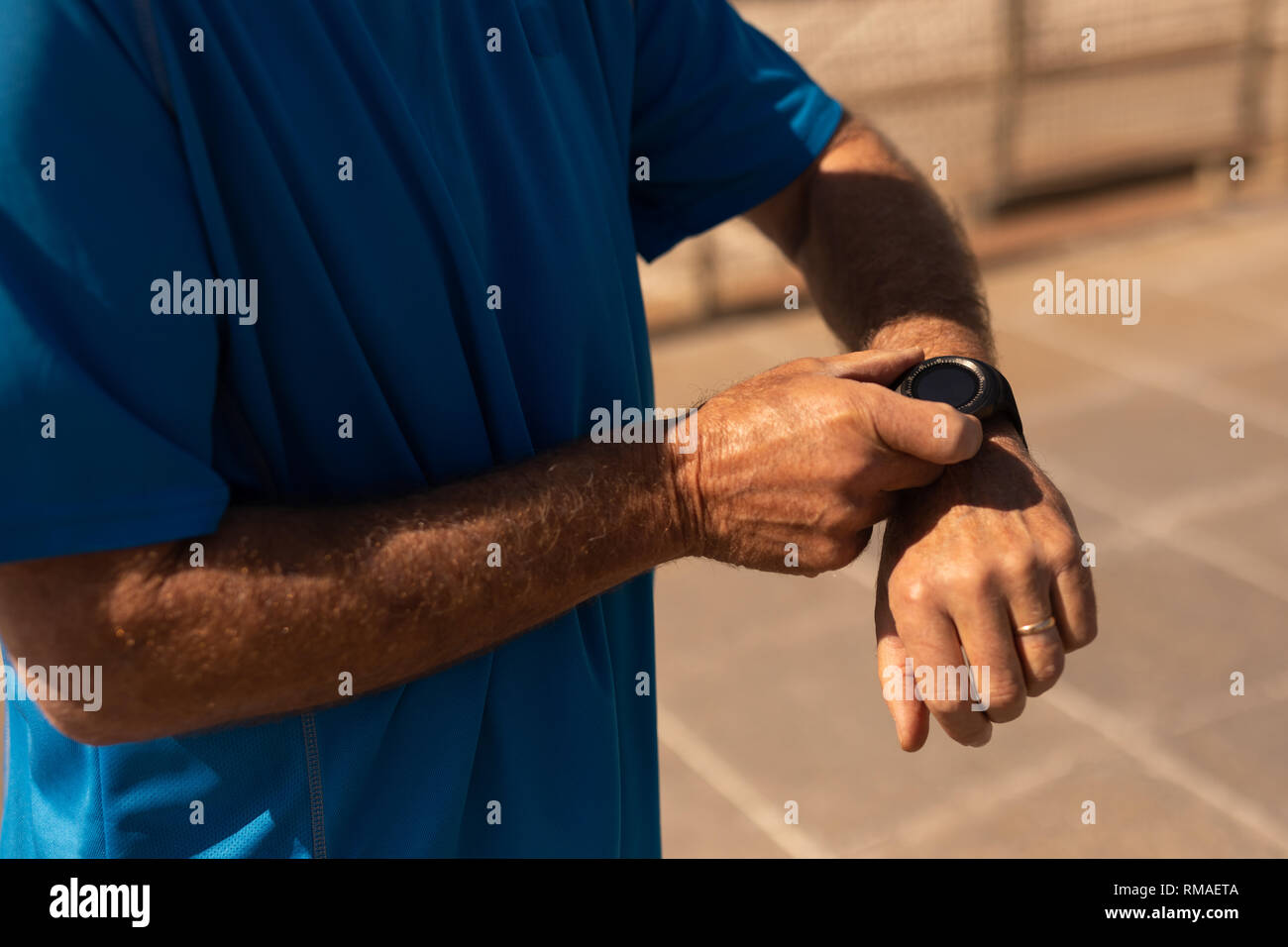 Mid section of man using smartwatch on a promenade at beach Stock Photo ...