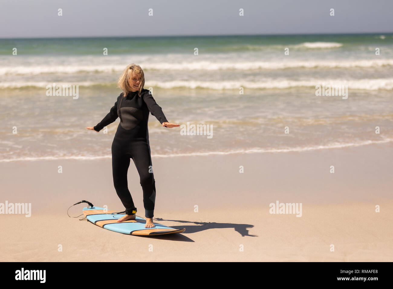 Side view of senior female surfer dancing on surfboard at beach Stock ...