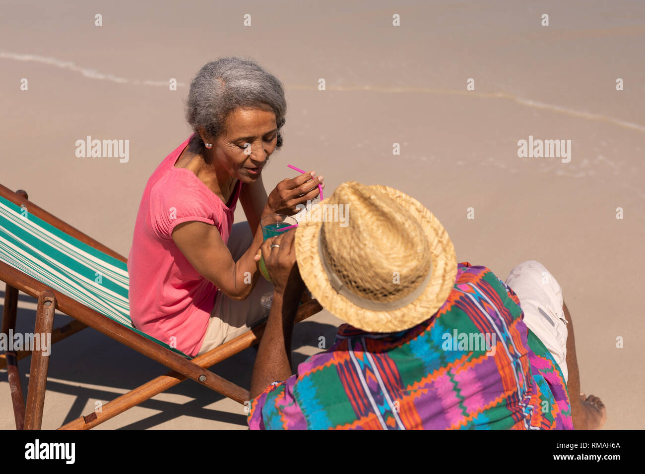 Senior couple relaxing on sun lounger and drinking cocktail on beach ...