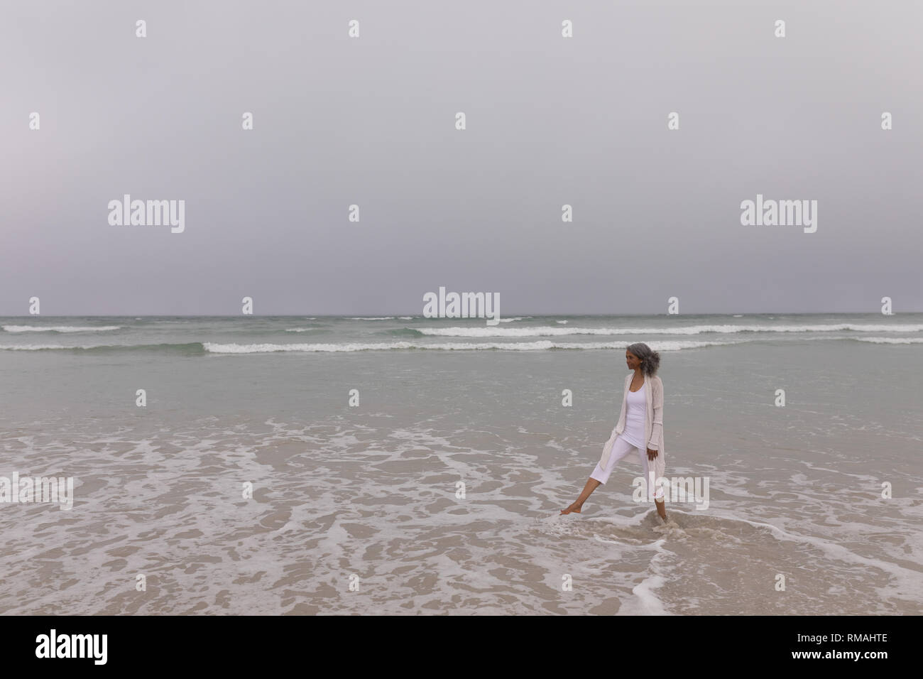 Senior woman splashing wave at beach Stock Photo - Alamy