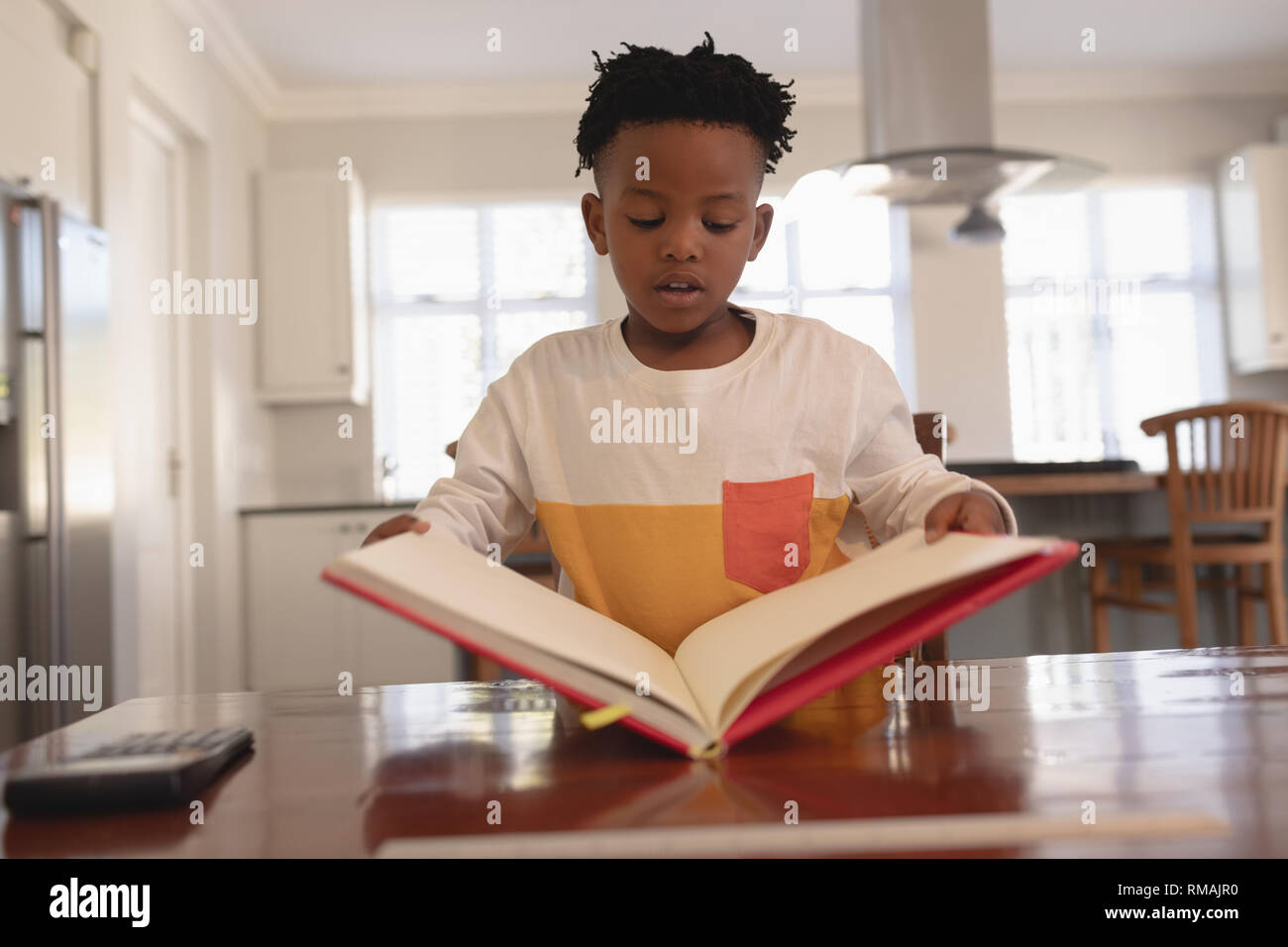 Cute African American boy open a book at table Stock Photo - Alamy