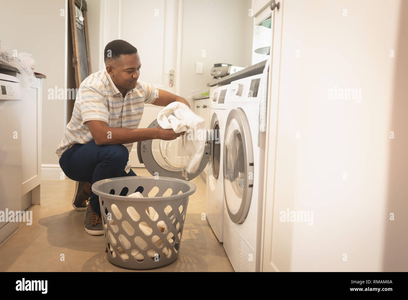 African American man washing clothes in washing machine Stock Photo - Alamy