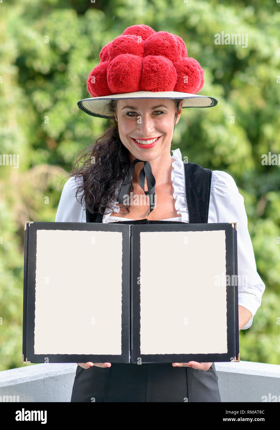A portrait of a beautiful german waitress holding a menu in traditional ...