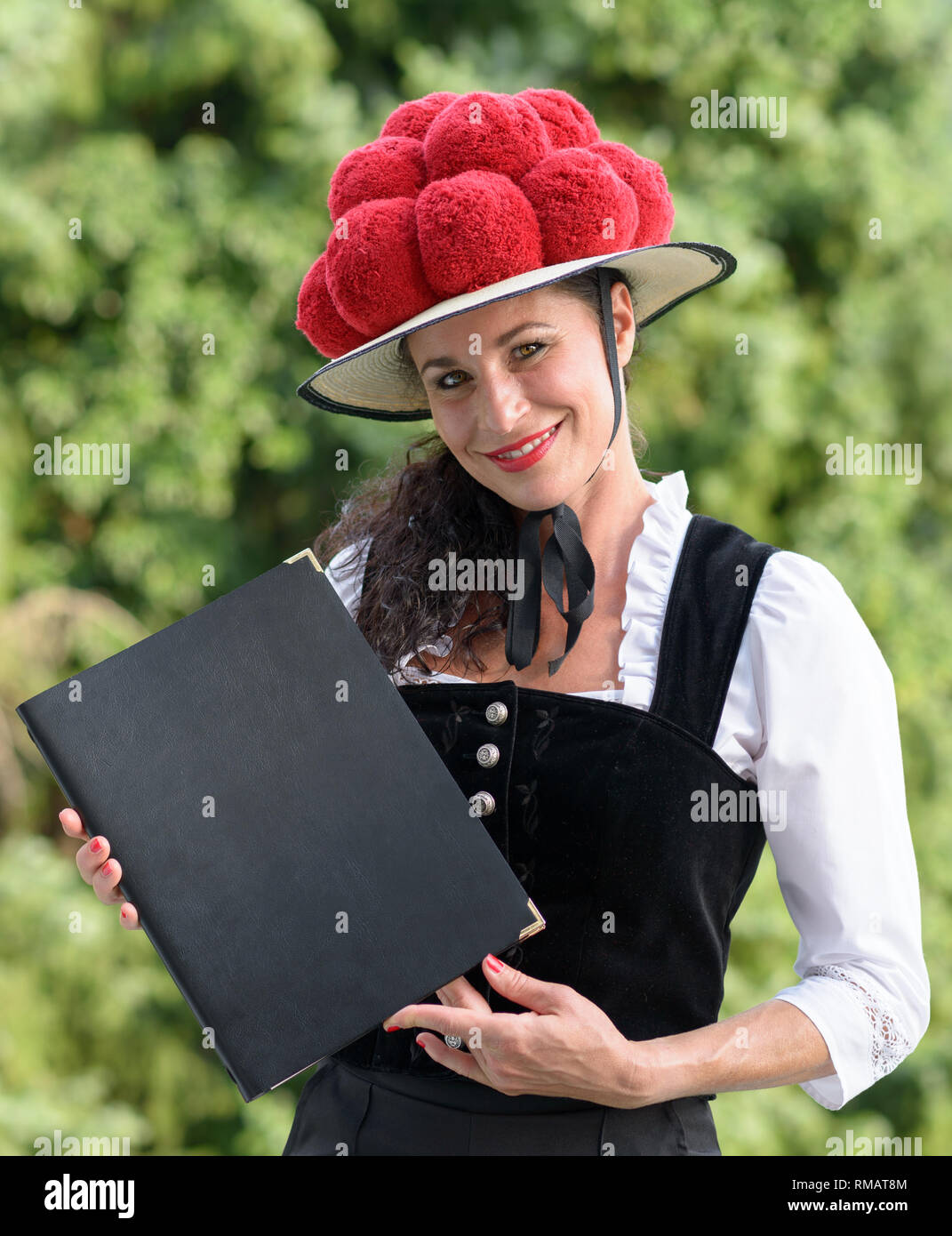 A portrait of a beautiful german waitress holding a menu in traditional ...