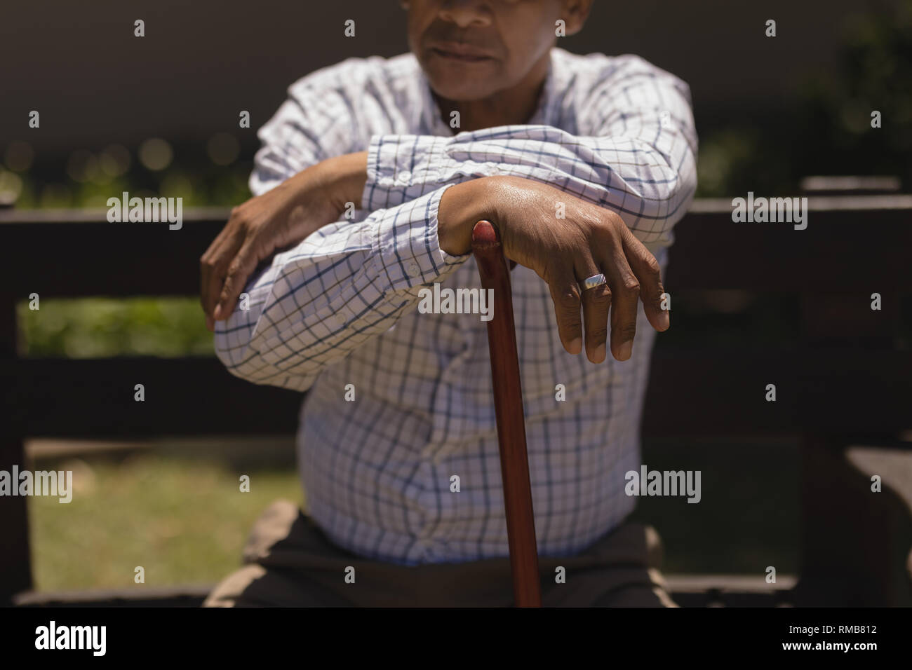 Mid section of senior man hands leaning on a cane while sitting on ...