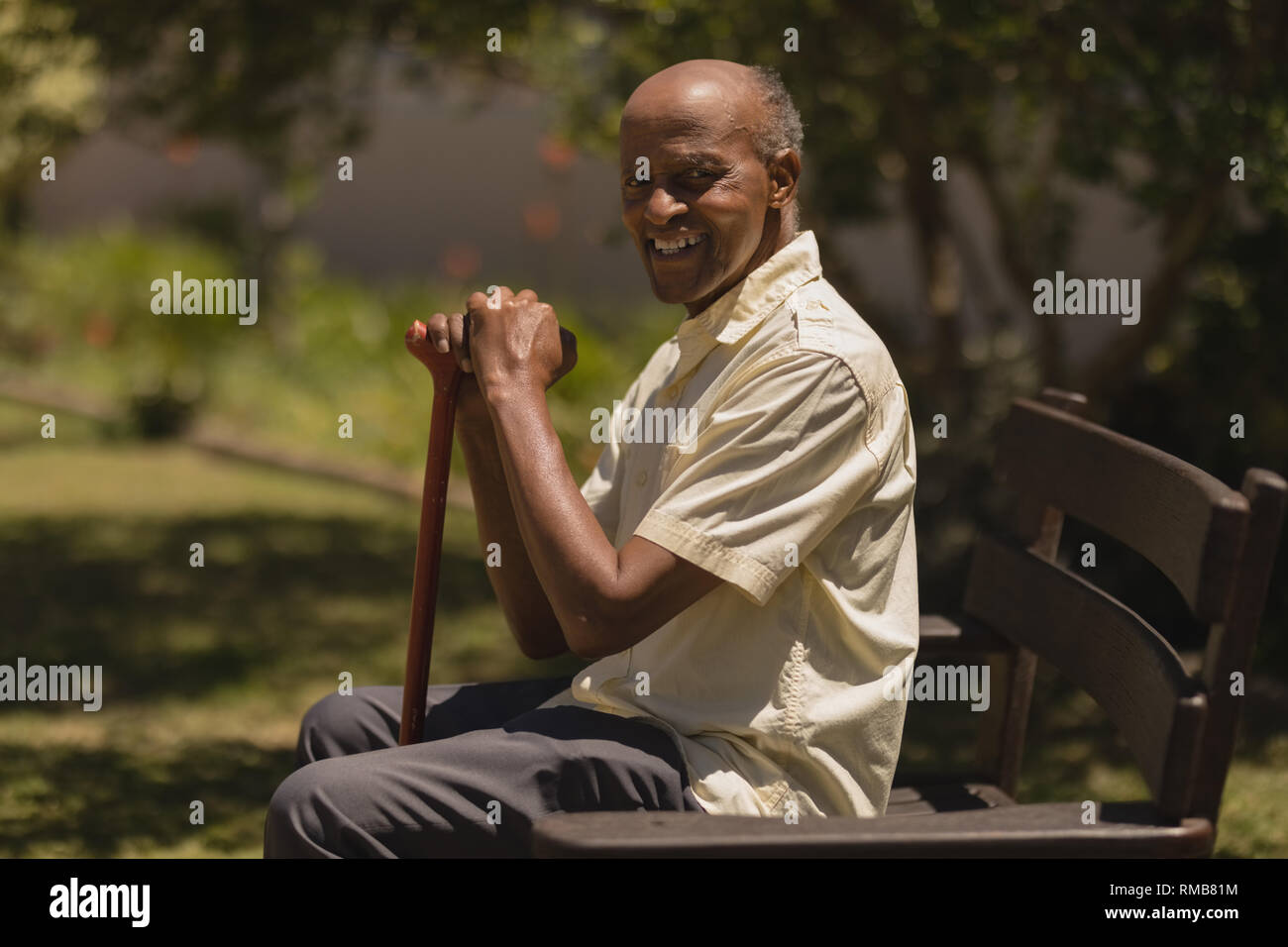 Side view of senior man hands leaning on a cane while sitting on bench ...