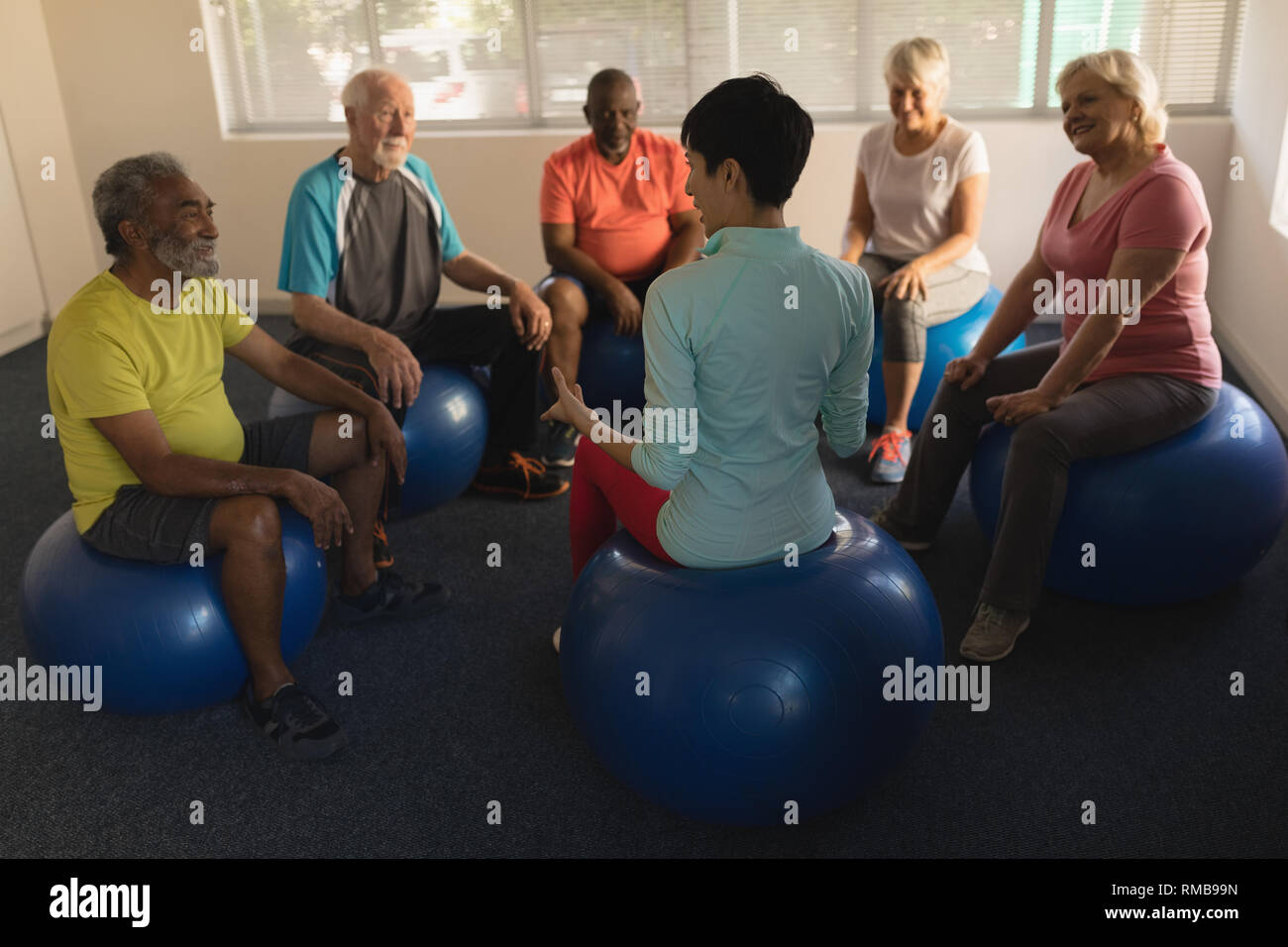 Female trainer training senior people in performing exercise Stock ...