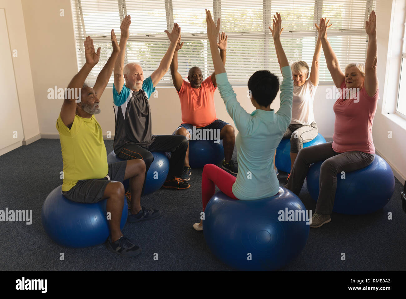 Female trainer training senior people in performing exercise Stock ...