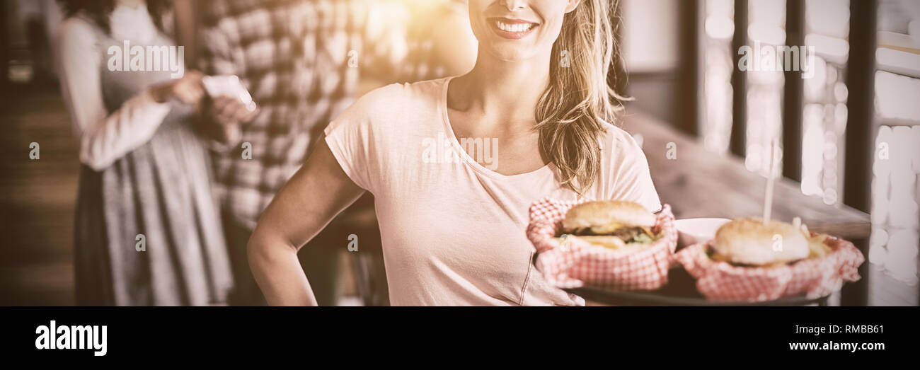 Smiling young waitress serving burger in restaurant Stock Photo - Alamy